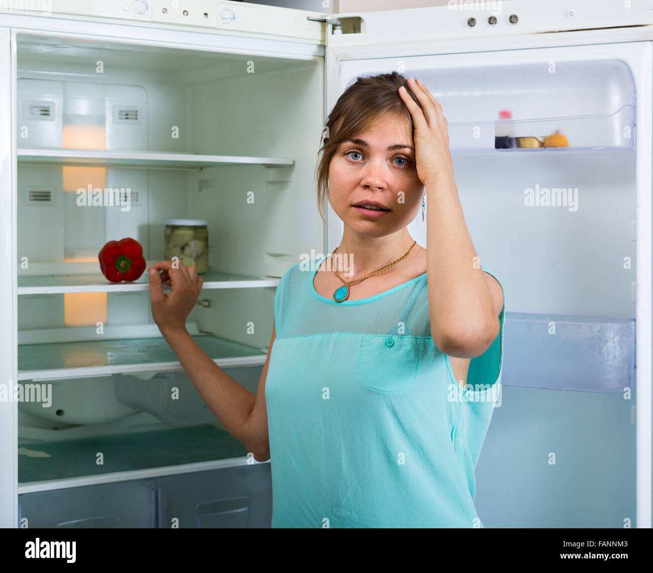Portrait of unhappy and hungry girl near empty fridge Stock Photo - Alamy