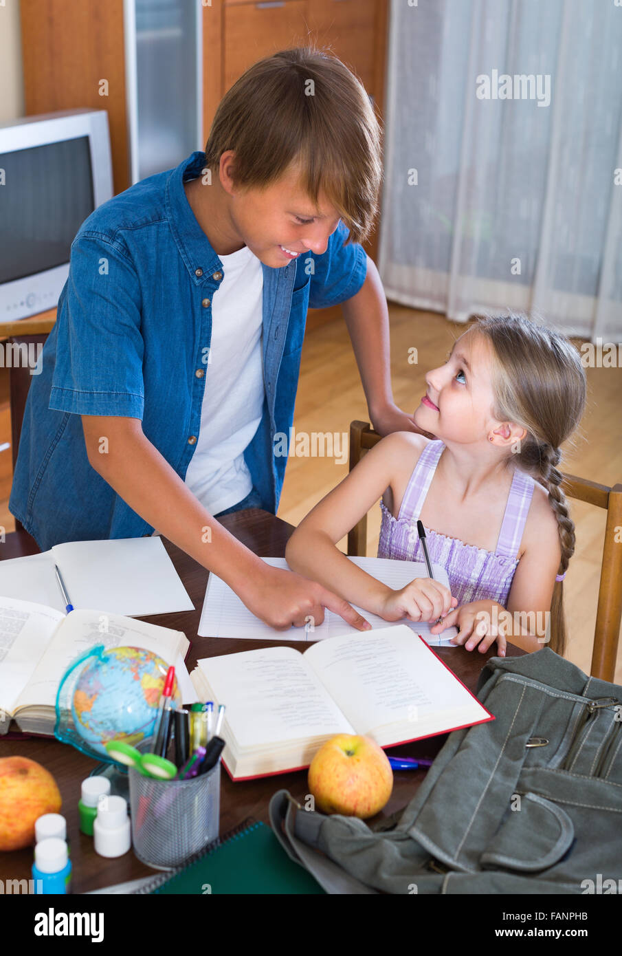 Smiling little brother and sister doing homework in domestic interior ...
