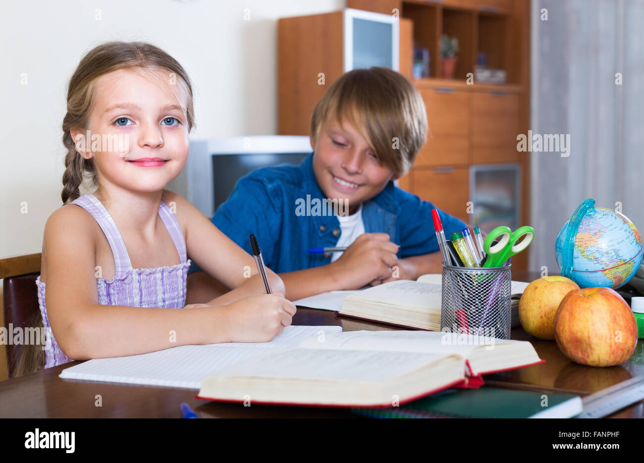 Smiling siblings doing homework with books at home Stock Photo - Alamy