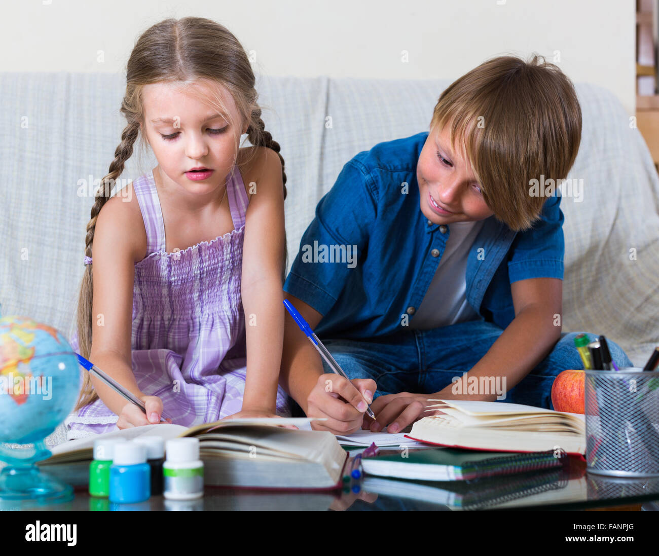Smiling boy and cute little girl doing homework together Stock Photo ...