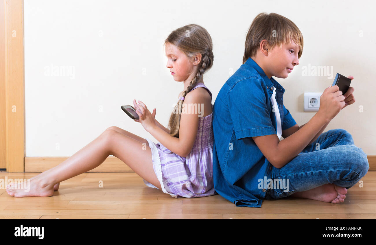 Two kids looking to smartphone screen at home Stock Photo - Alamy
