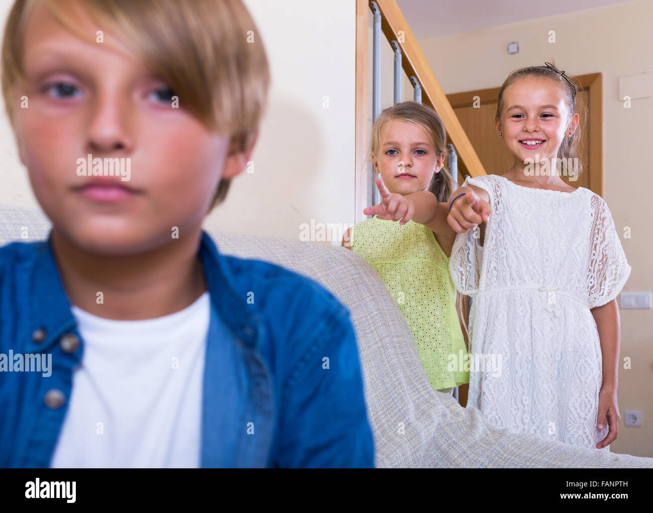 Two little girls talking and sulky boy sitting separately at home ...