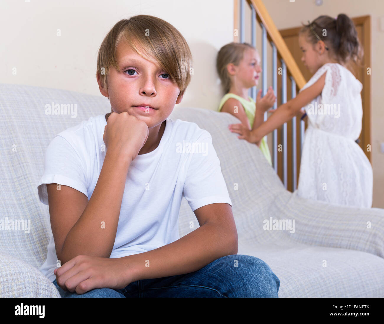 Two little american girls talking and sulky boy sitting separately at ...