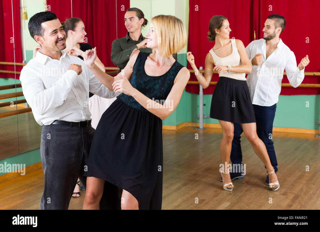 Tree smiling european couples dancing rock-and-roll in dancing-class ...