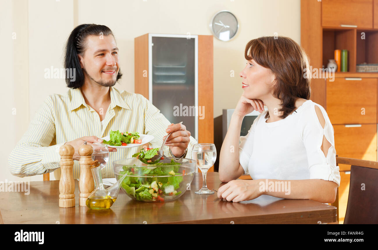 Brunette beautiful woman with man eating veggie salad at home Stock ...