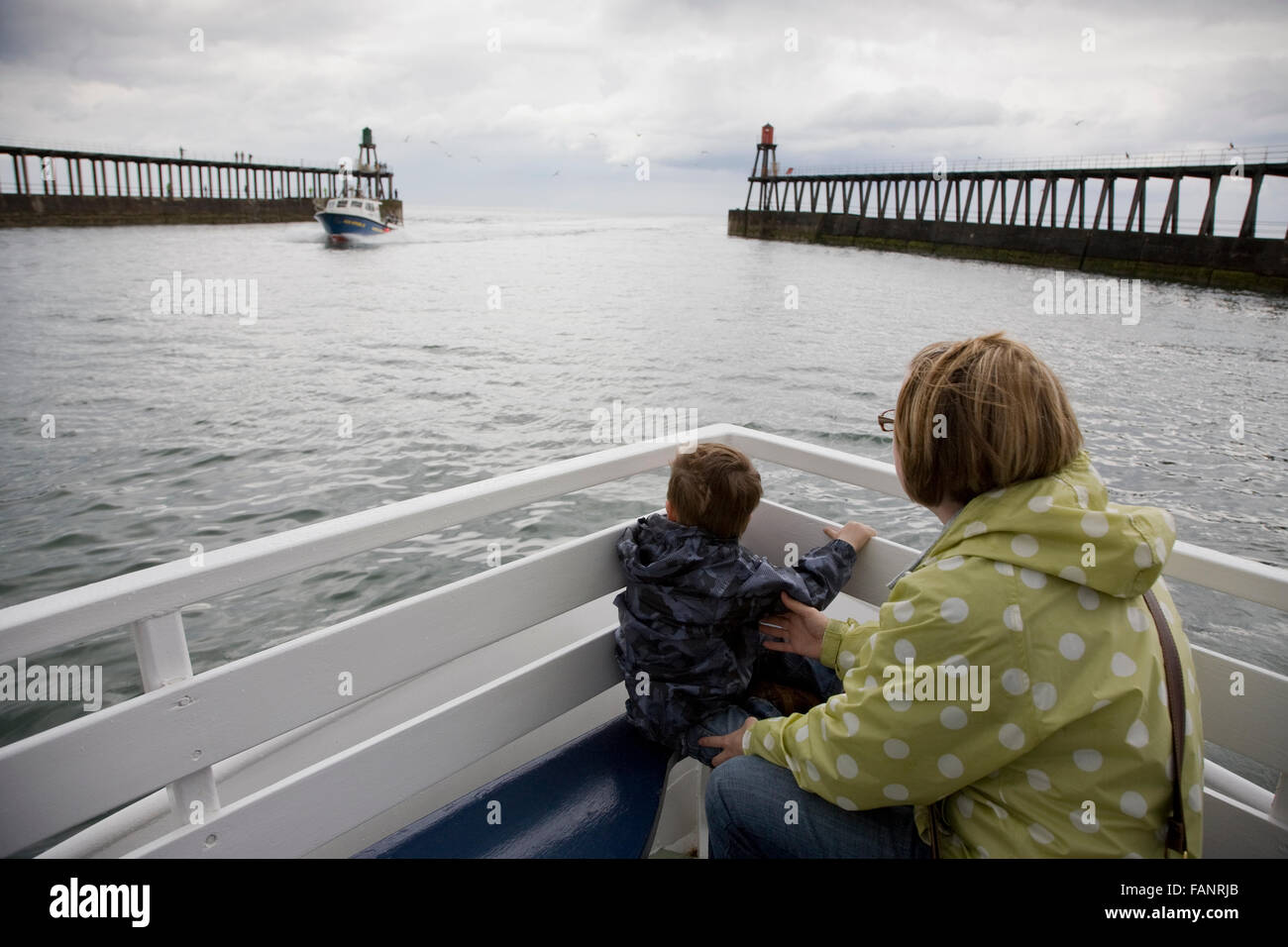 A mother and her son take a boat ride on a grey day out of the harbour ...