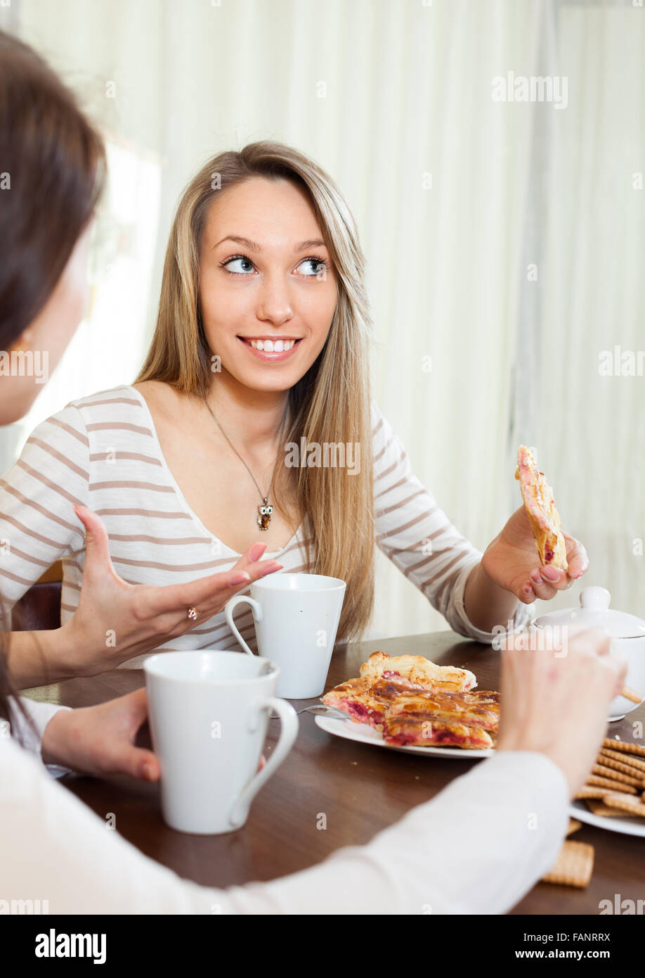 two happy girls drinking tea and gossiping in home Stock Photo - Alamy