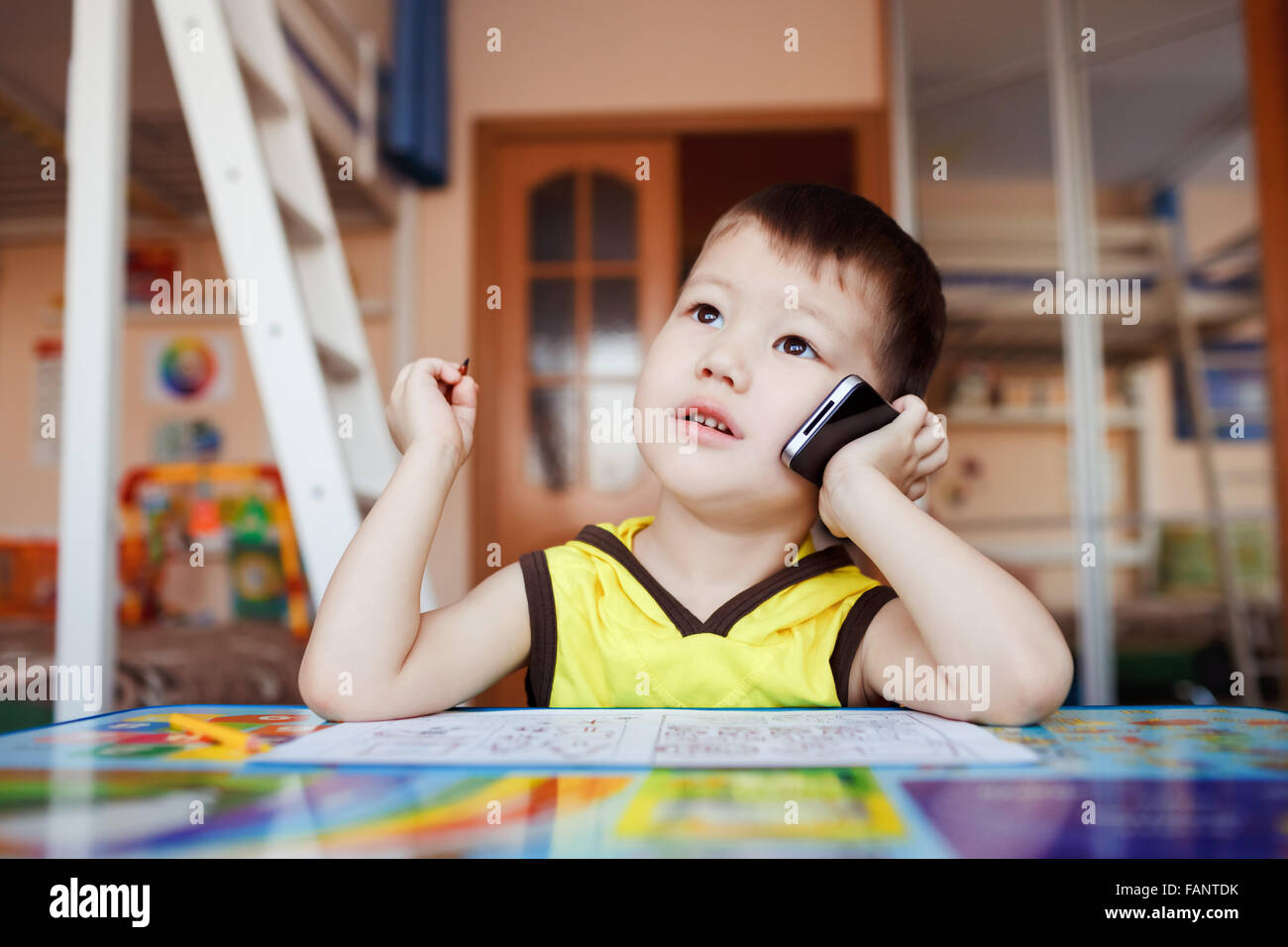 Little boy takes an important call on his cell phone, while drawing at ...
