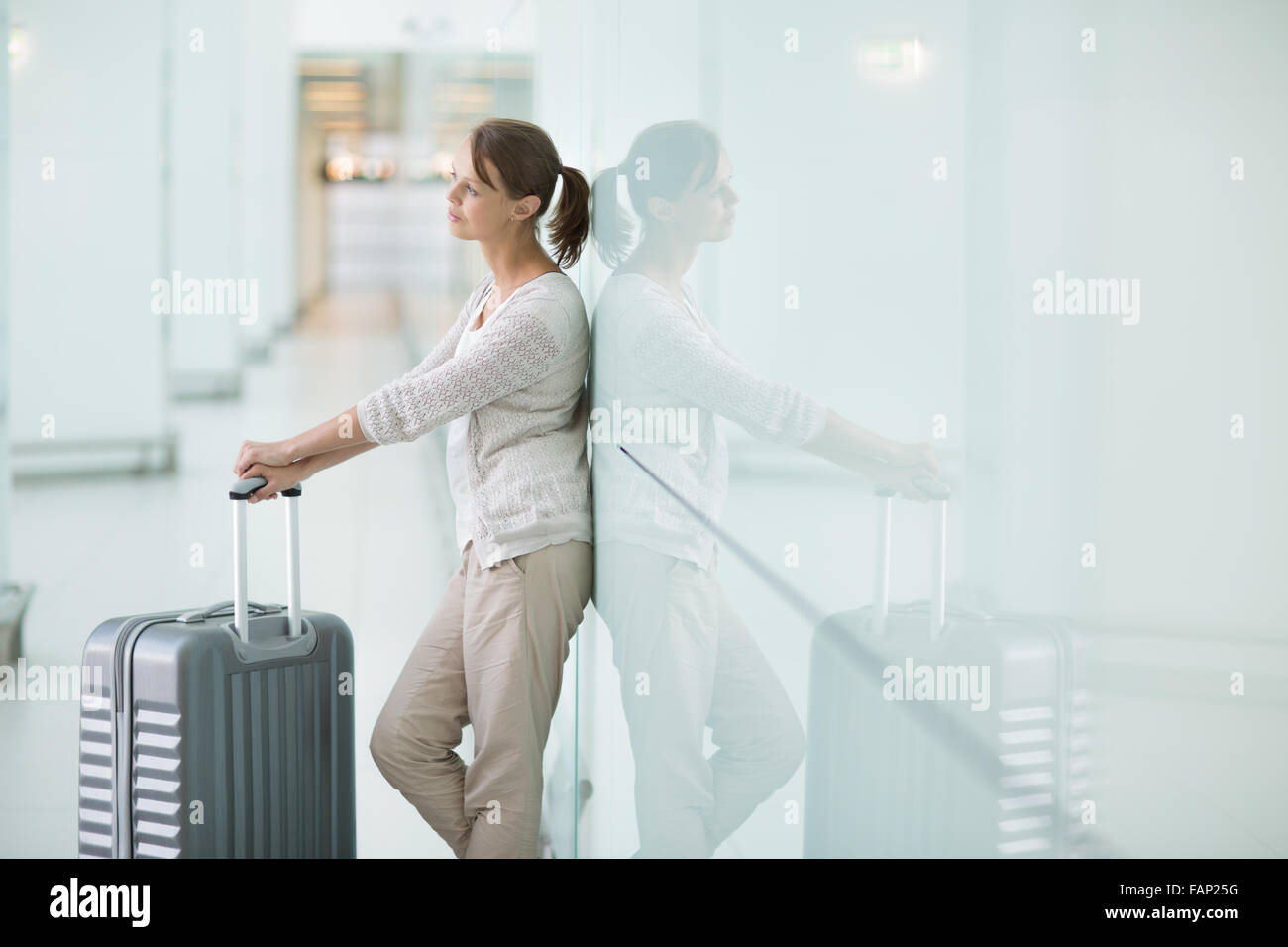 Young female passenger at the airport, waiting for her delayed flight ...