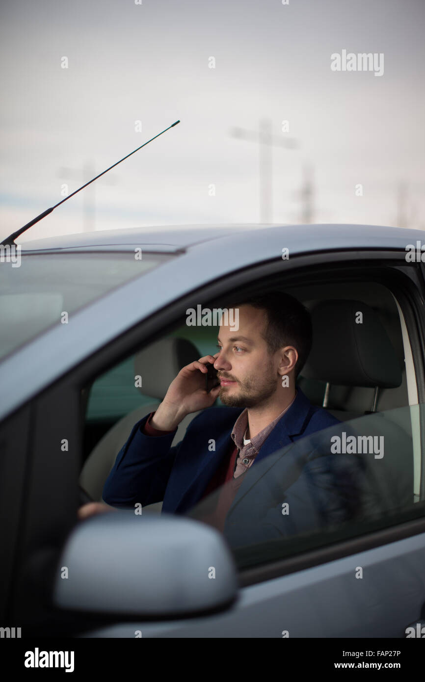 Handsome young man calling on his cellphone while at the wheel of his ...