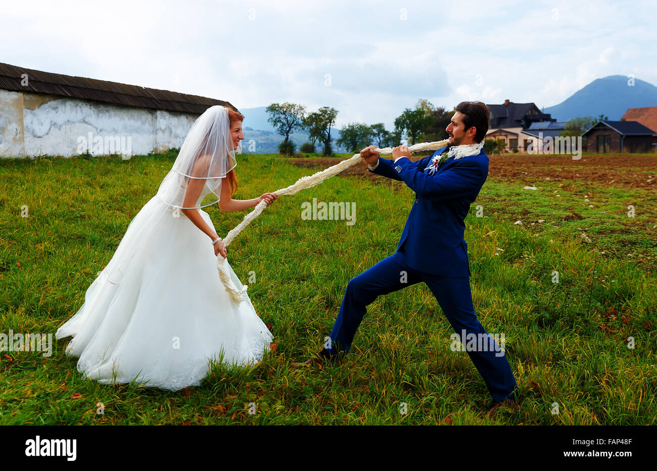 bride pulling her groom to her with a rope - funny wedding concept ...