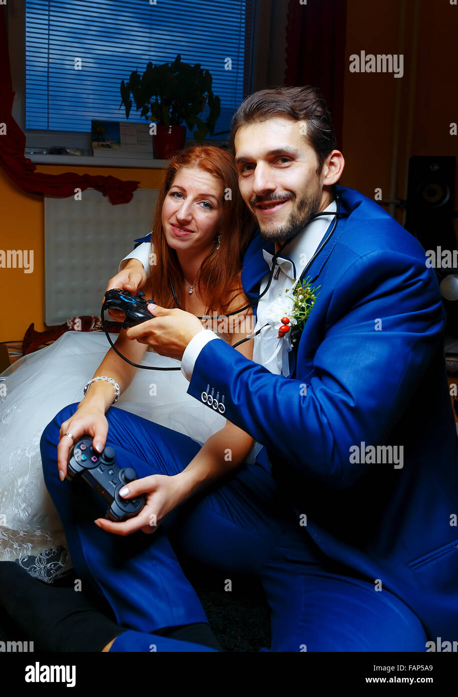 bride and groom playing together videogames with joysticks - gaming and ...