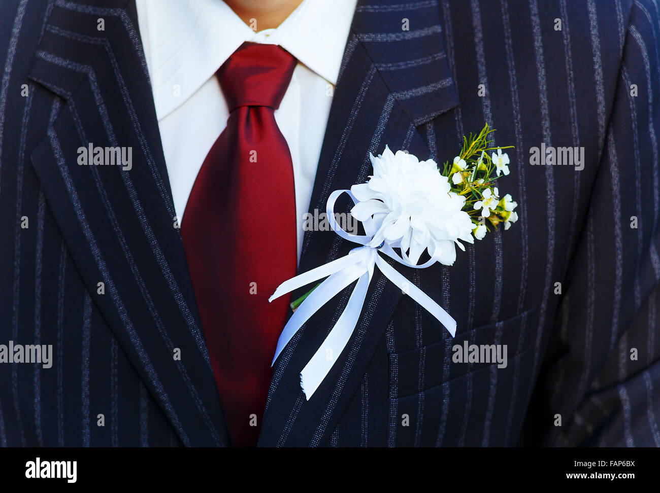 close-up black jacket groom on their wedding day with a red tie and ...