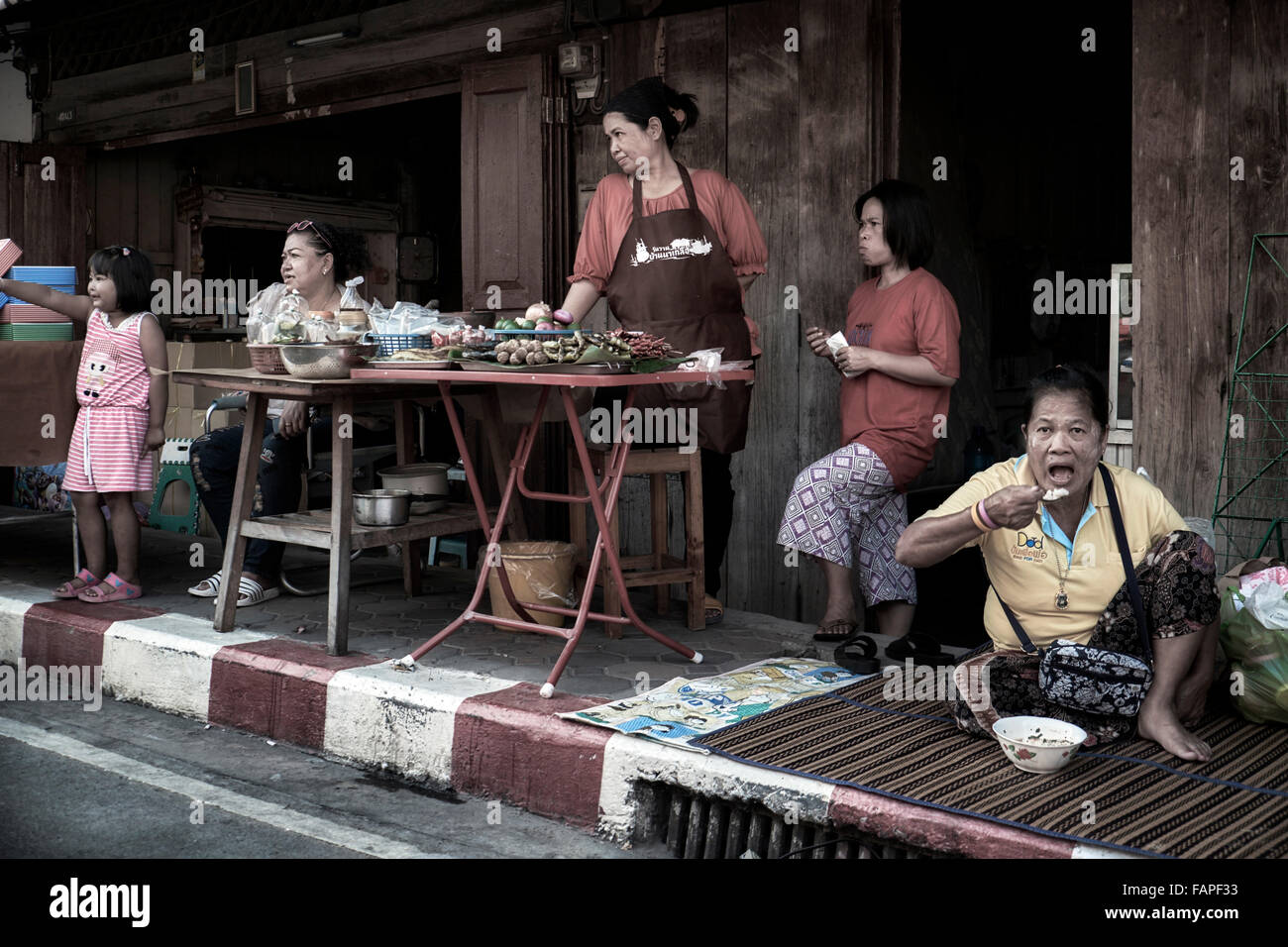 Thailand family with food being sold and consumed from the pavement ...