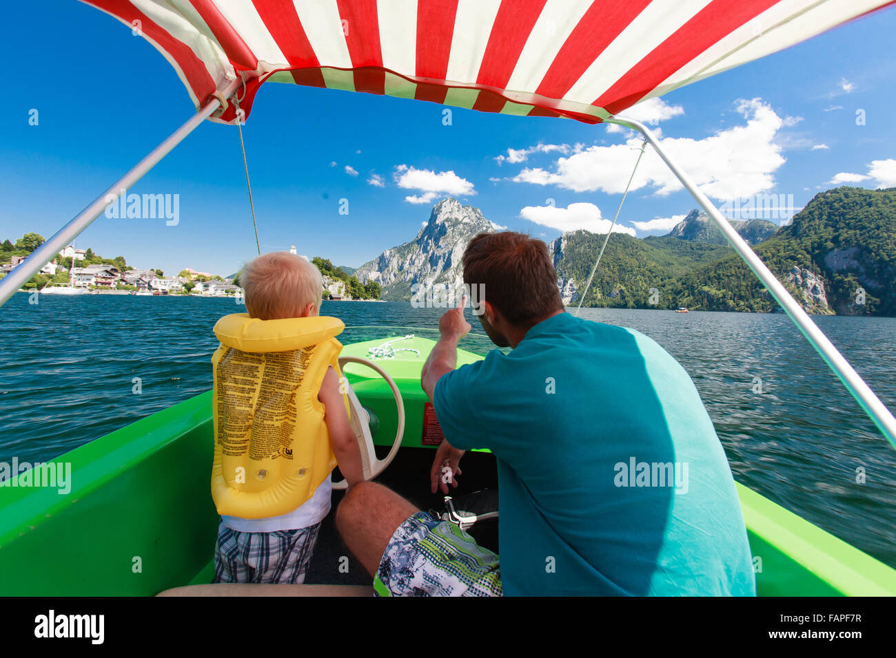 Little boy drives water boat on alpine lake Stock Photo - Alamy