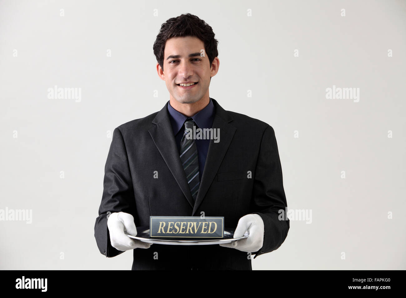 Studio portrait of waiter holding reserved sign Stock Photo - Alamy