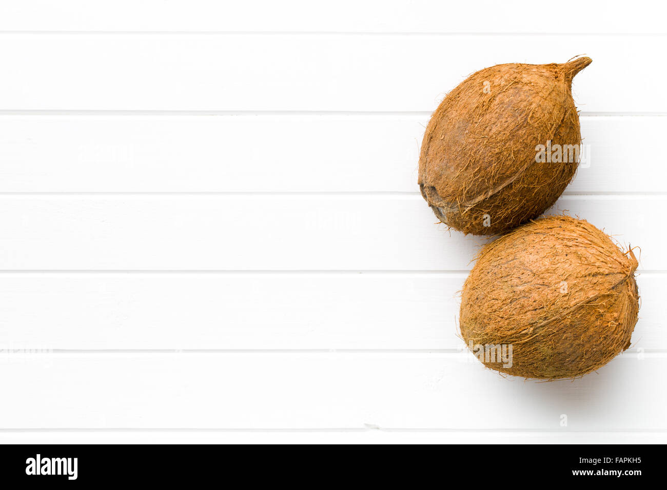 whole coconuts on white kitchen table Stock Photo - Alamy