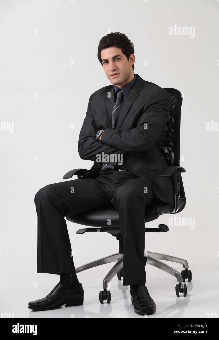 Business man sitting on office chair crossing arm Stock Photo - Alamy