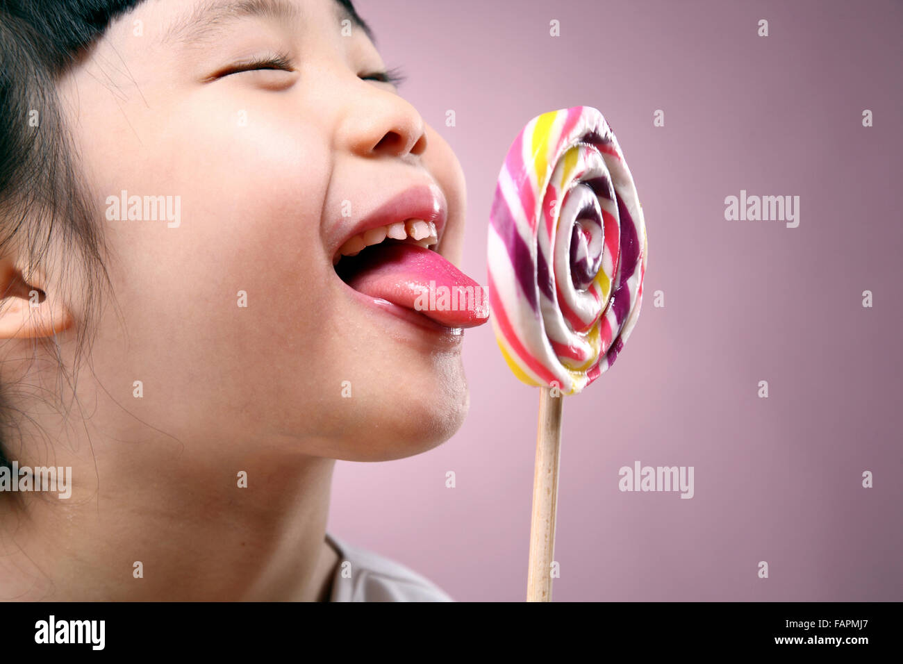 girl having fun licking lollipop Stock Photo - Alamy