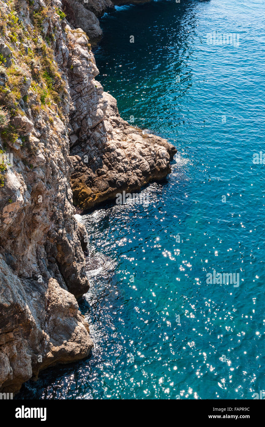 The steep rocky, cliffs around Dubrovnik fall into the clear waters of ...