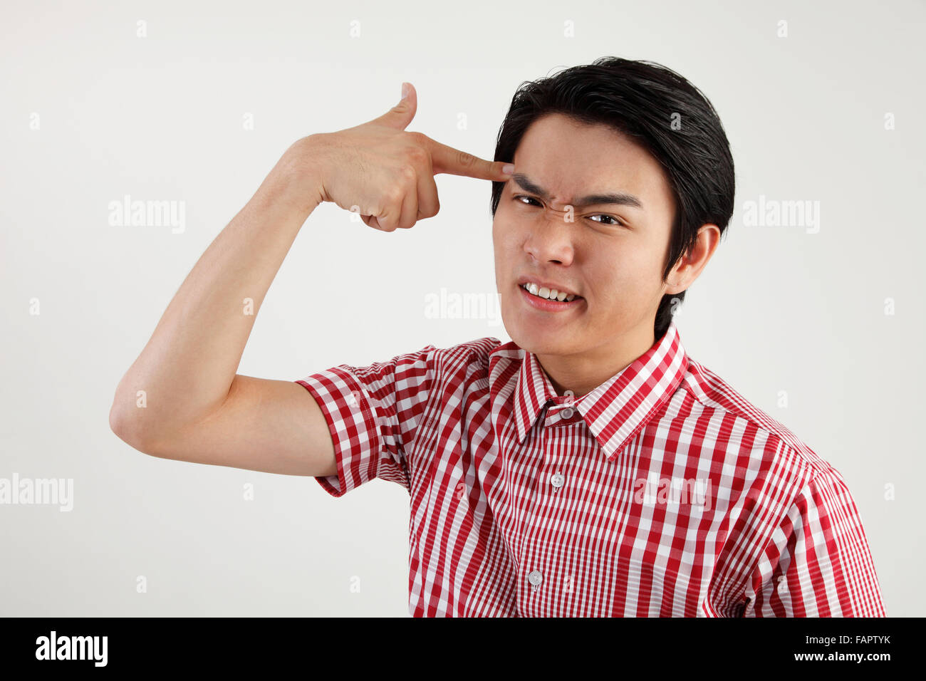 Man pointing at side of head, gritting teeth Stock Photo - Alamy