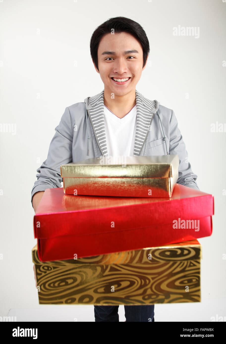 Young man carrying stack of gifts, smiling, portrait Stock Photo - Alamy