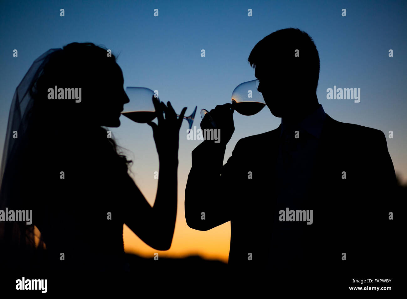 Bride and groom drinking wine at sunset Stock Photo - Alamy