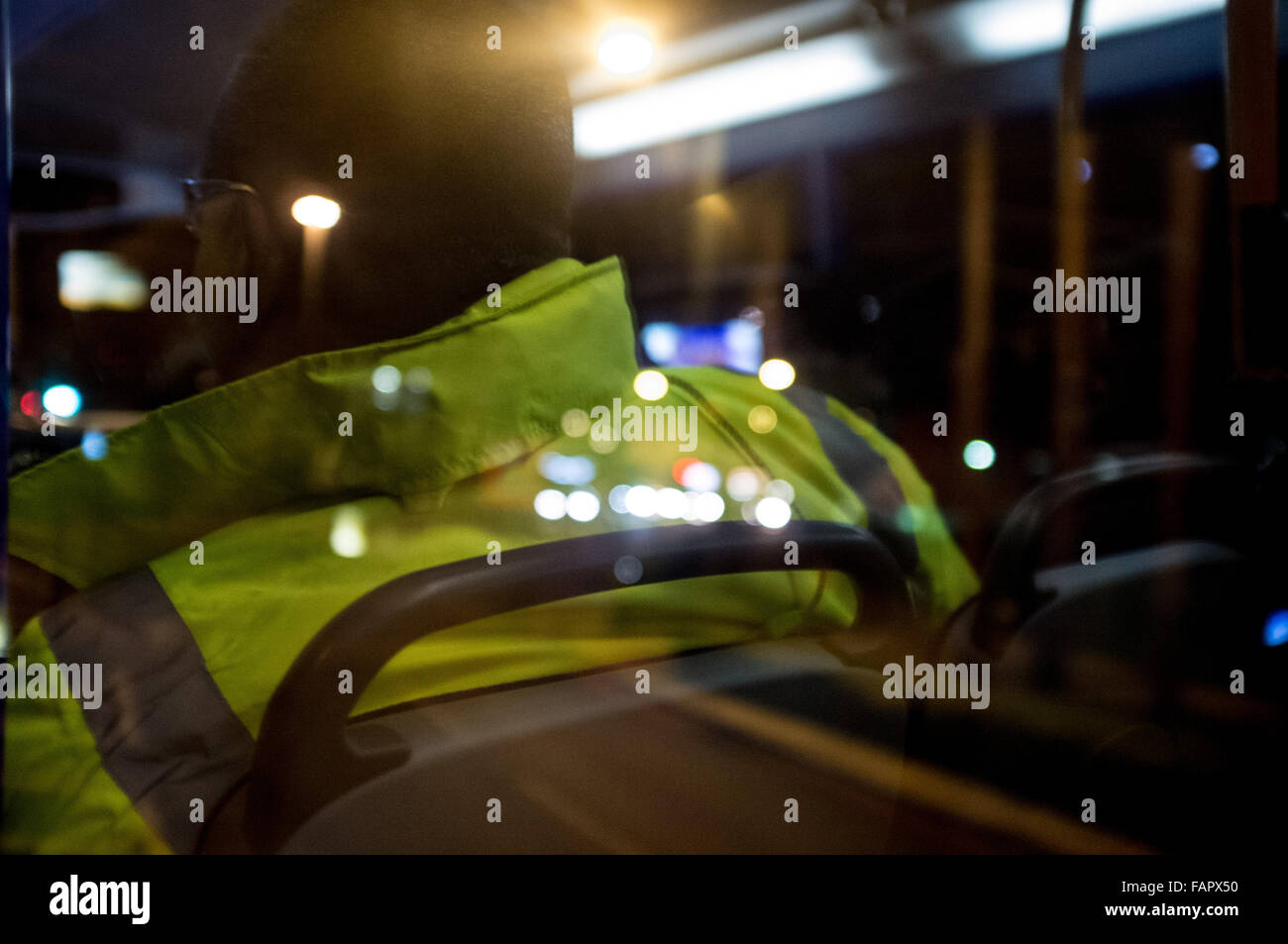Lights reflected in construction worker's yellow reflective jacket on ...