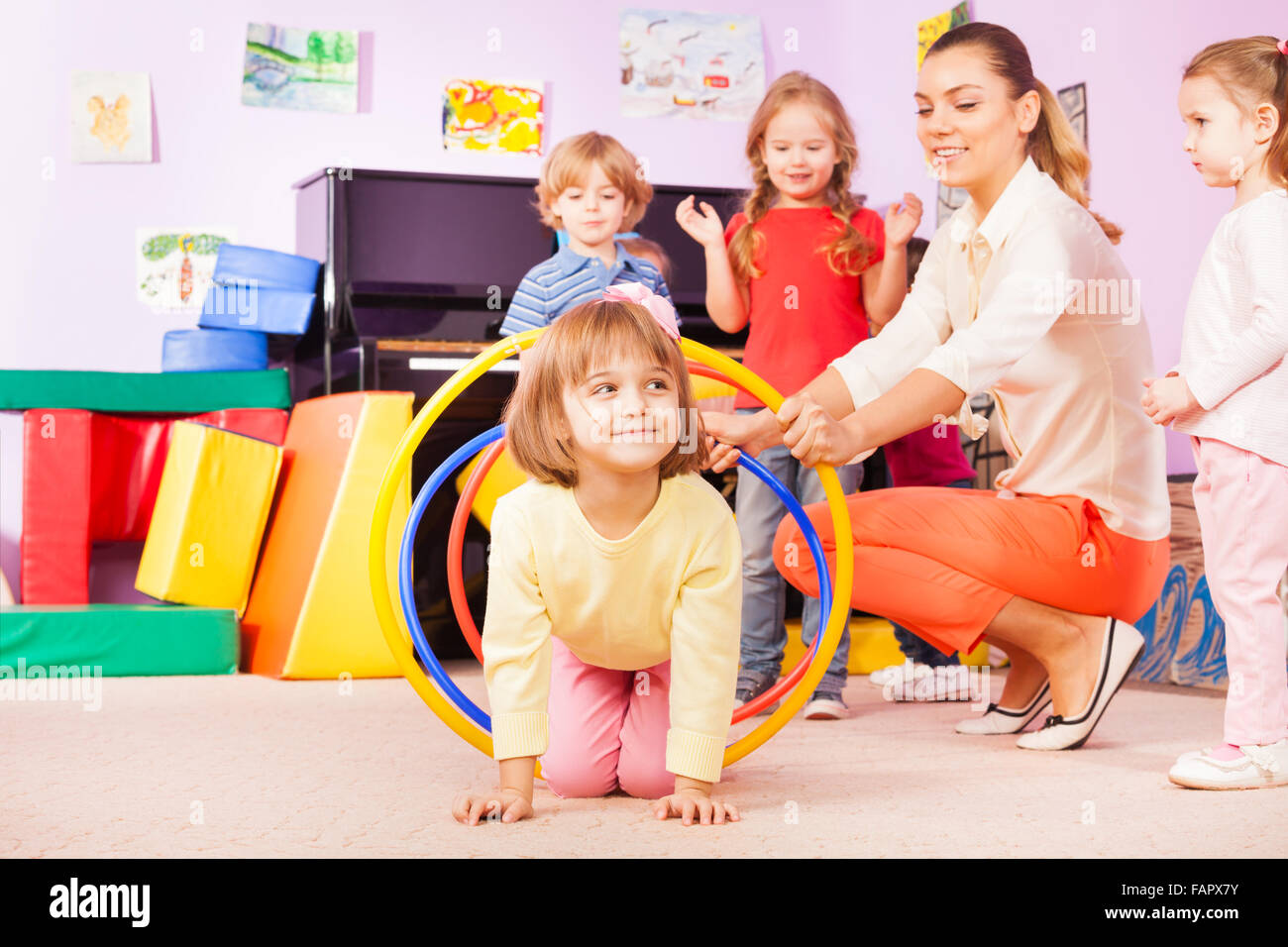 Girl crawl in plastic hoop, kindergarten group Stock Photo - Alamy
