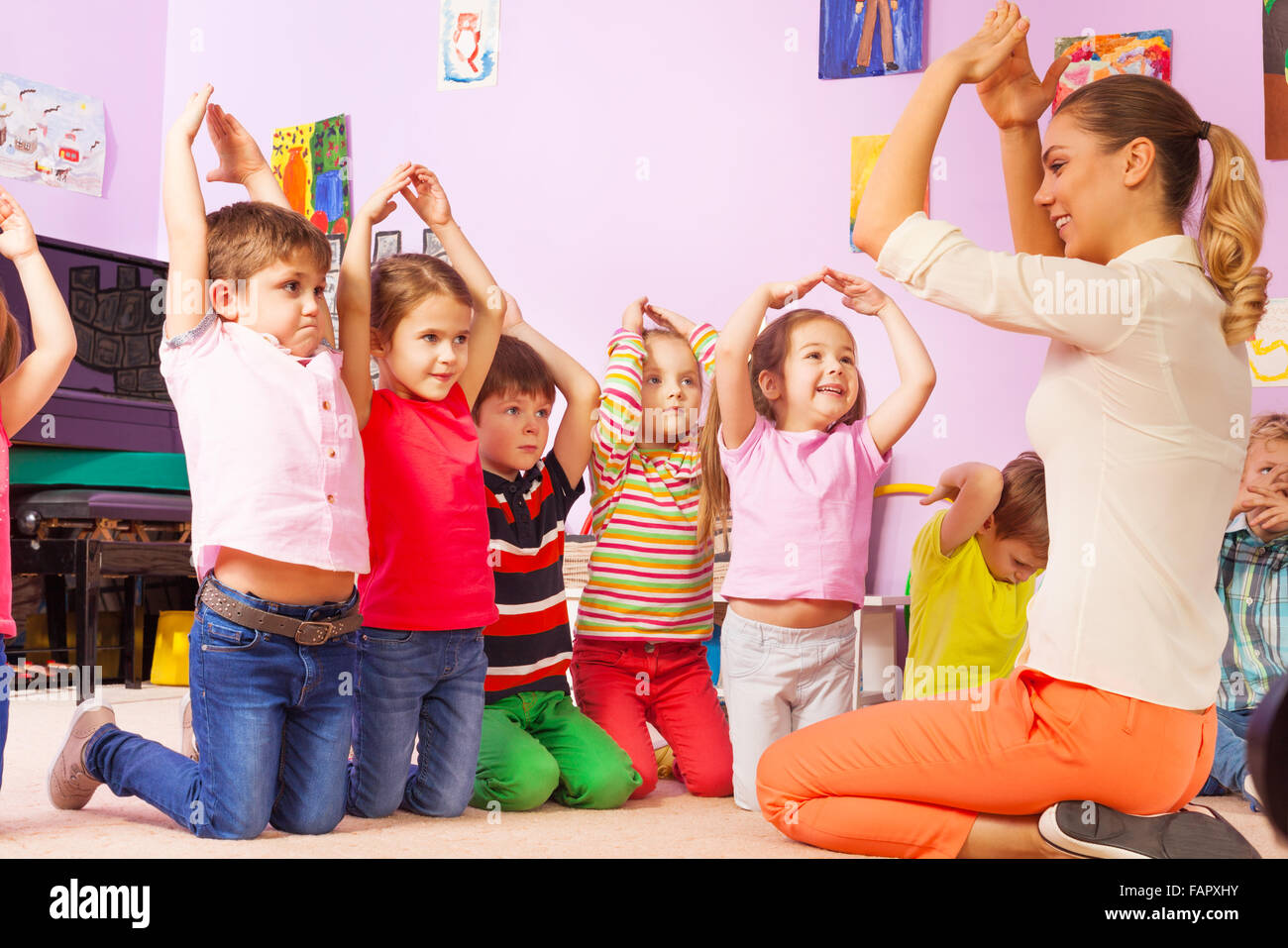 Group of kids repeat gesture after the teacher Stock Photo - Alamy