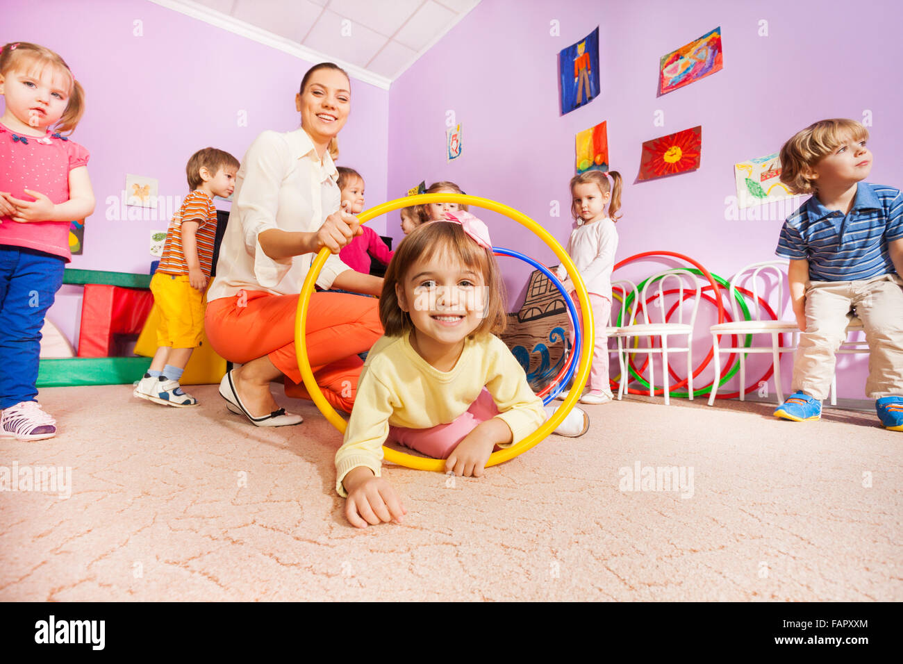 Little girl and other kids crawl though hoops Stock Photo - Alamy