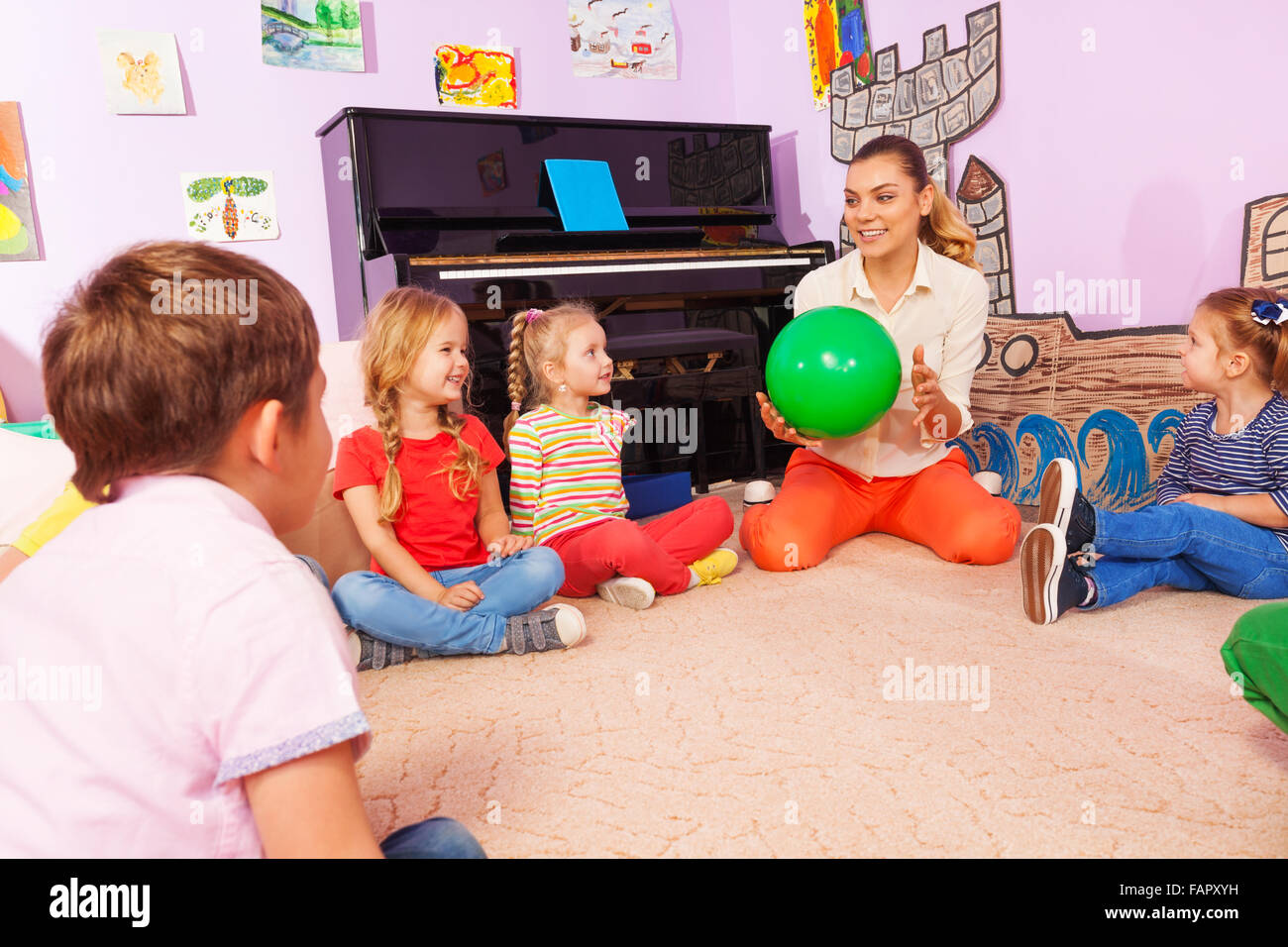 Teacher and kids sit in circle play with ball Stock Photo - Alamy