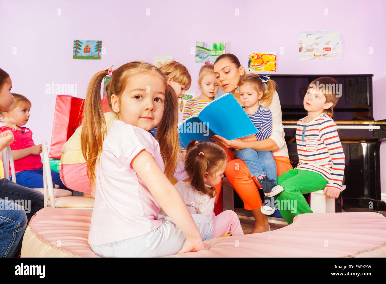 Group of kids listen to teacher reading book Stock Photo - Alamy