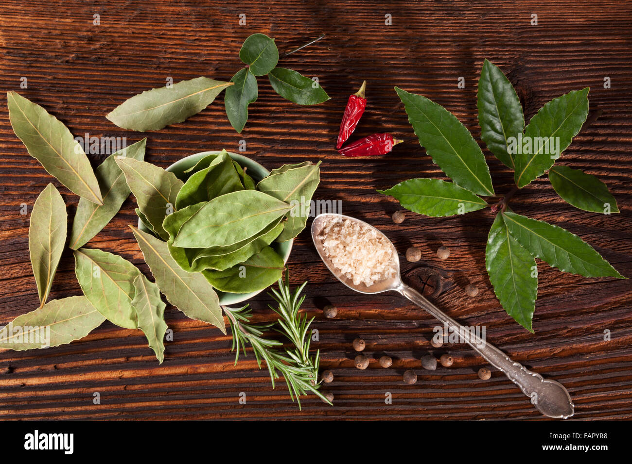 Traditional spice and condiment wooden background. Bay leaves, rosemary ...