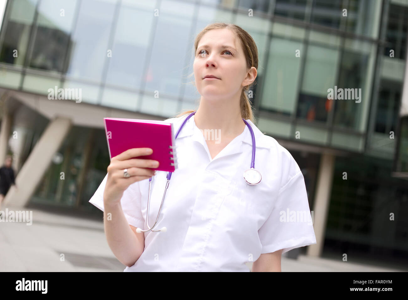 young doctor holding a notepad looking thoughtful Stock Photo - Alamy