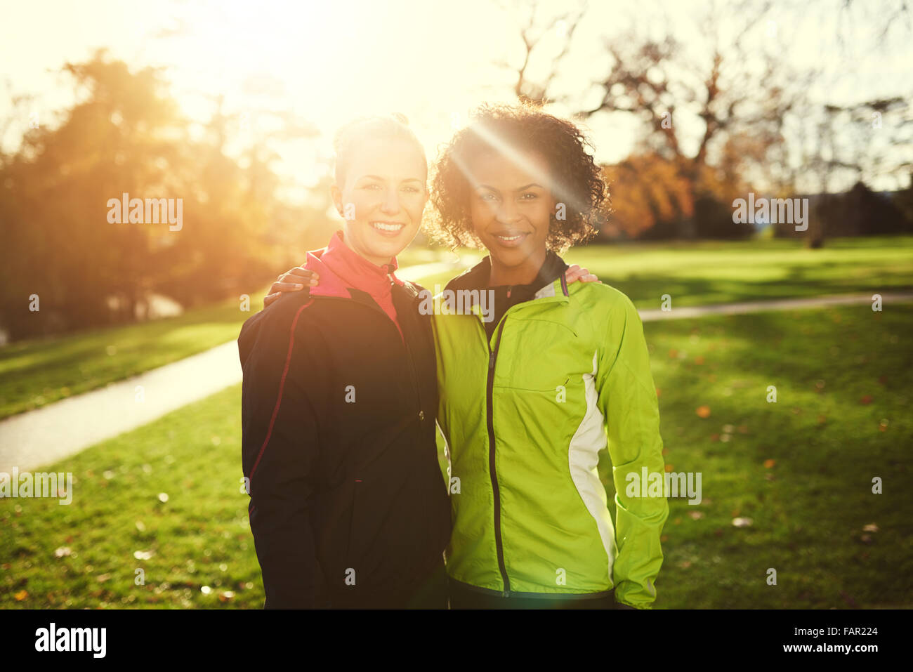 Two young female athletes hugging and smiling at camera while standing ...