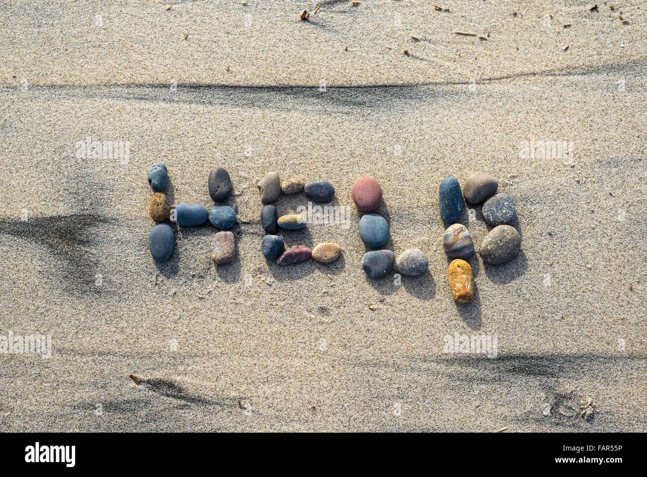 The word HELP spelled out in stones on the sand Stock Photo - Alamy