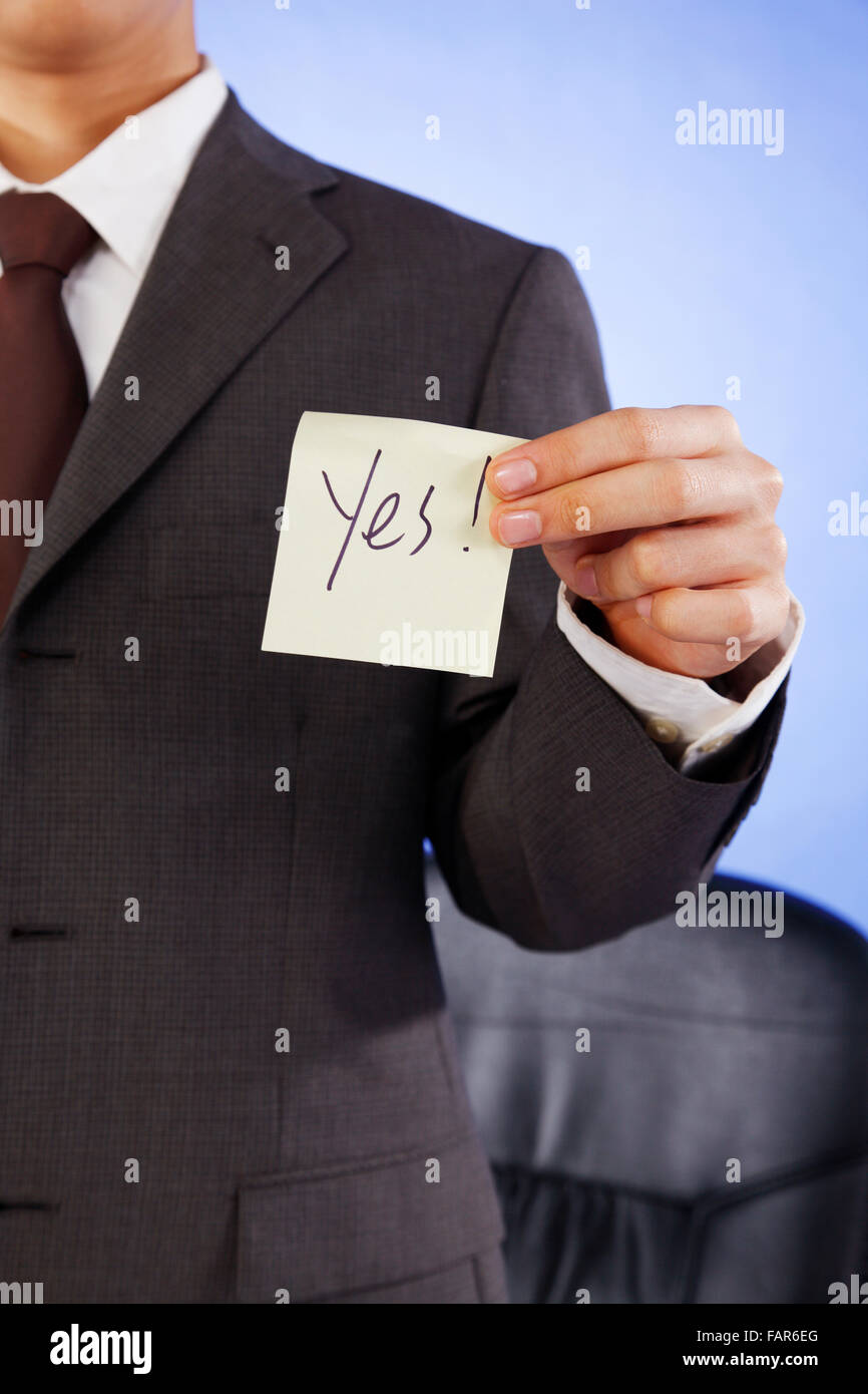 holding up a yellow Post-It note that says, 'YES.' Stock Photo - Alamy