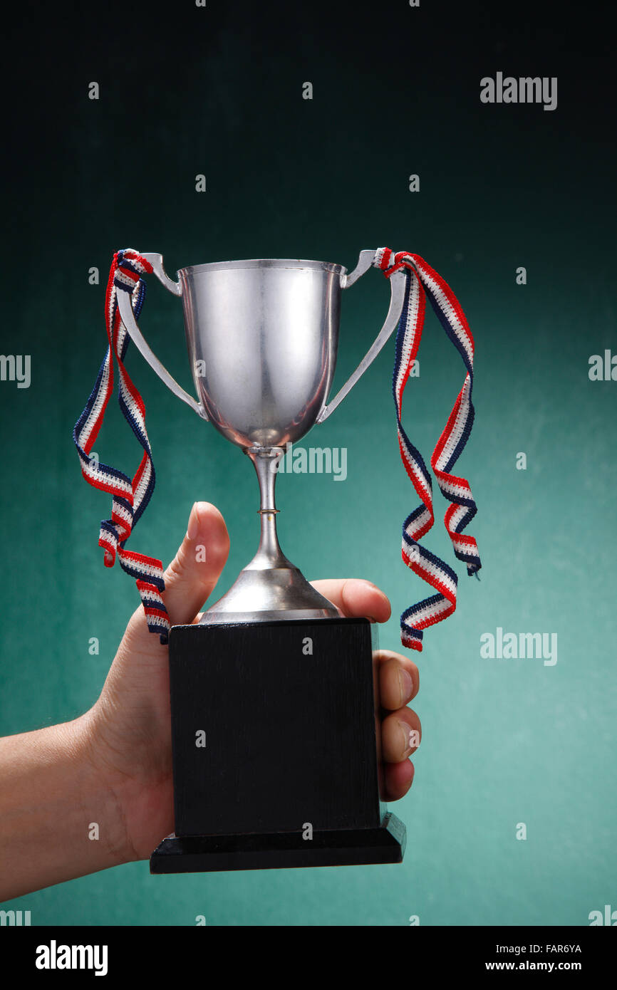 Human hand holding a silver trophy Stock Photo - Alamy