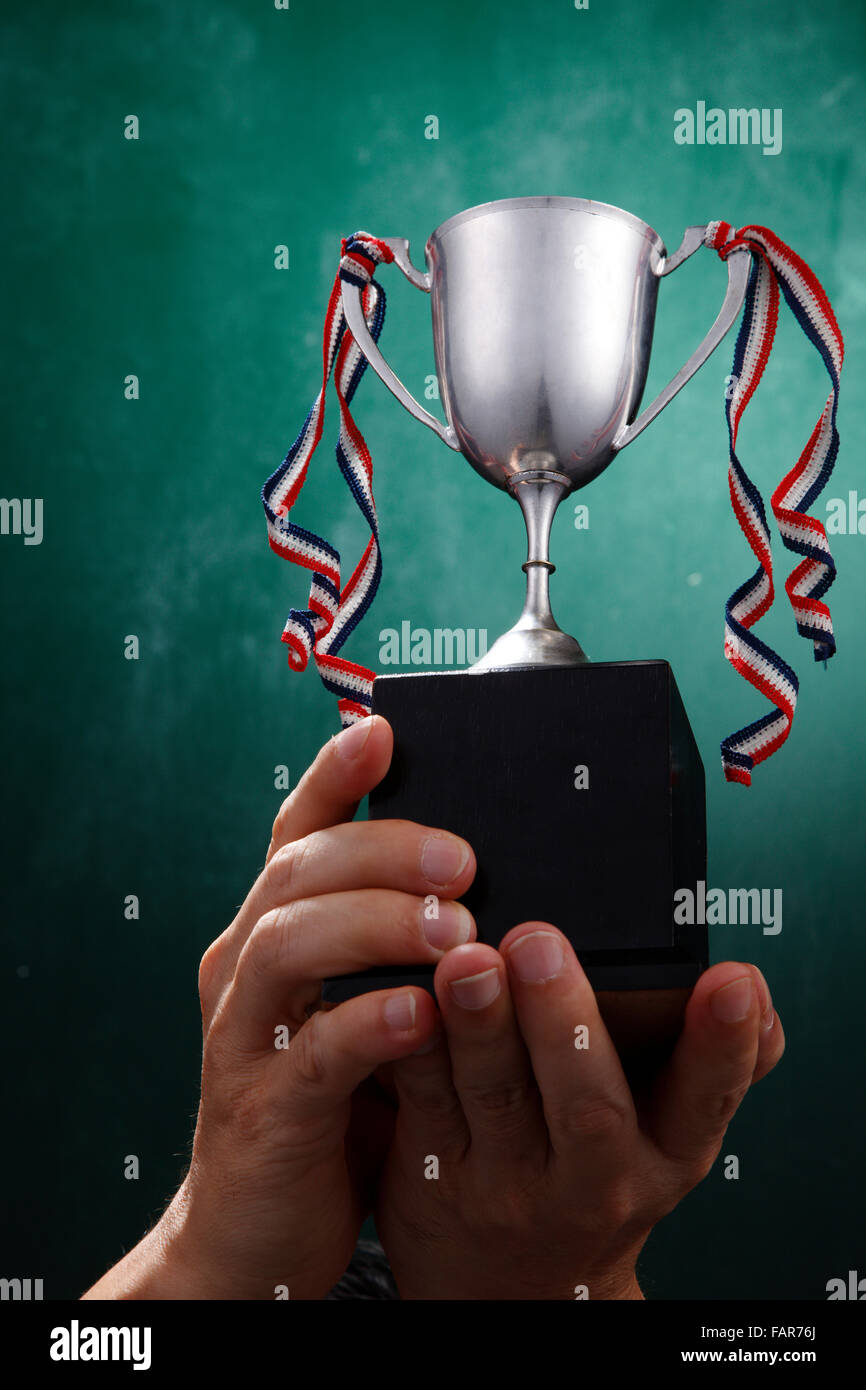 Human hand holding a silver trophy Stock Photo - Alamy