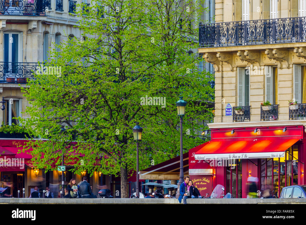 people relaxing on wall edging Île Saint-Louis in the Seine River at dusk in Paris Stock Photo ...