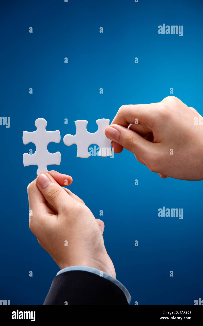 Human hand fitting two puzzle pieces together Stock Photo - Alamy