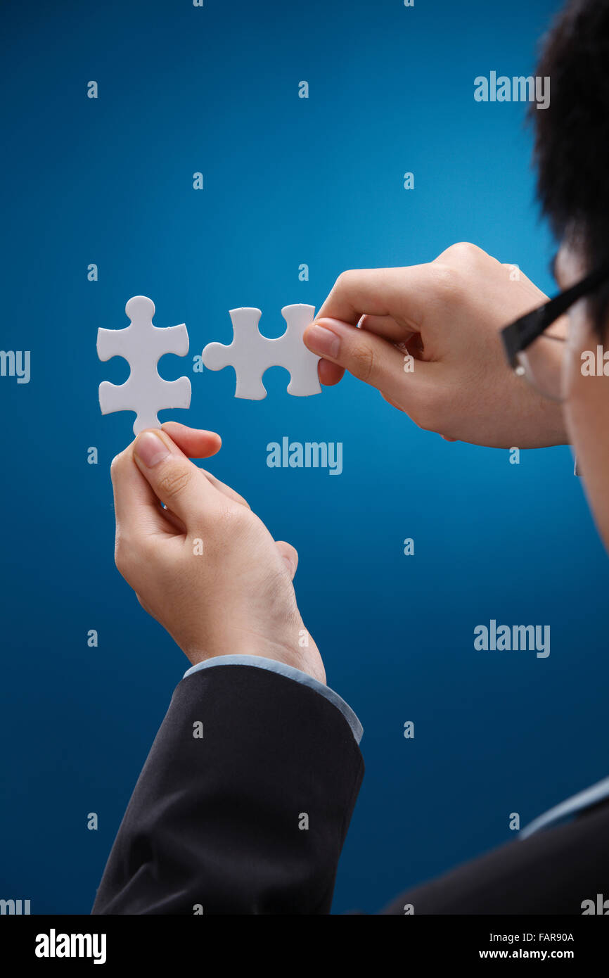 Human hand fitting two puzzle pieces together Stock Photo - Alamy