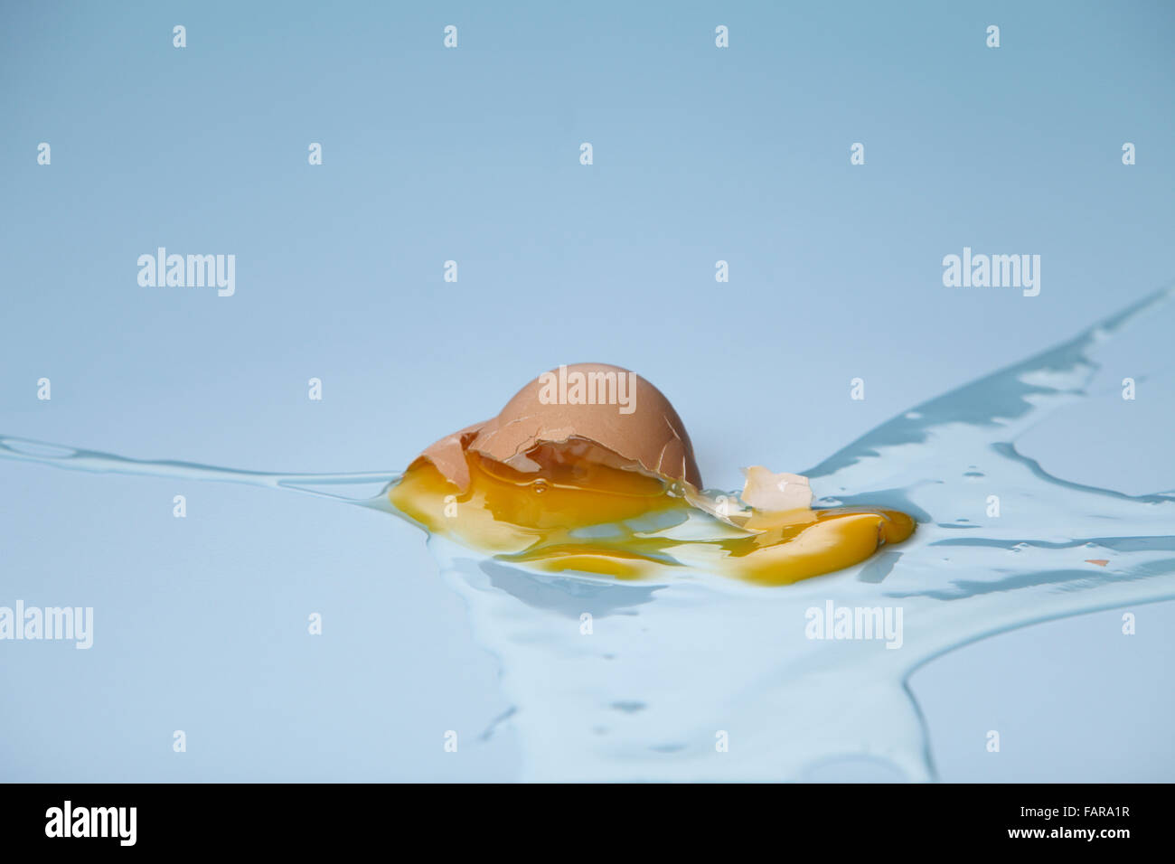 Splattered egg isolated on blue background Stock Photo - Alamy