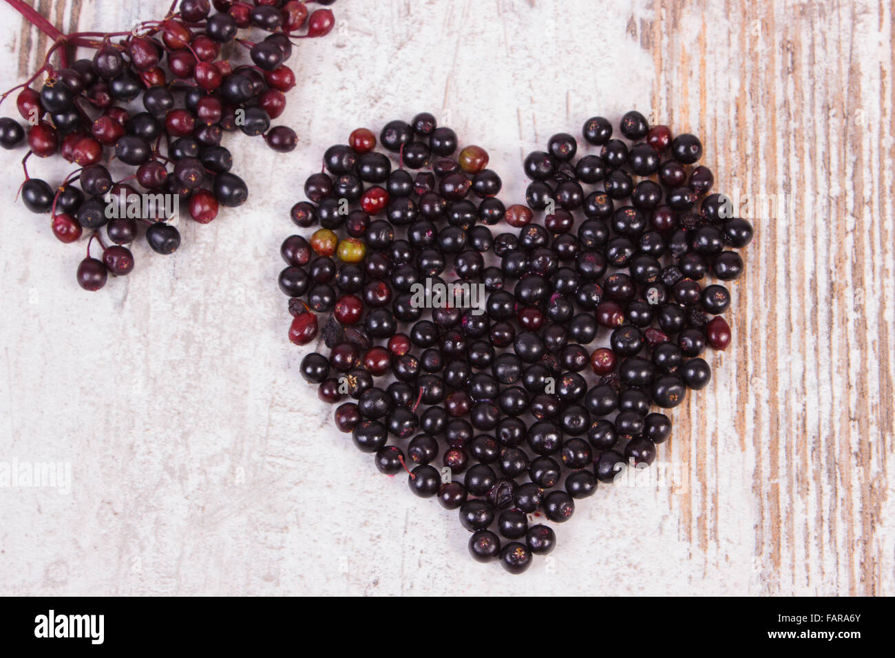 Heart shaped fresh elderberry on old rustic wooden background, symbol ...