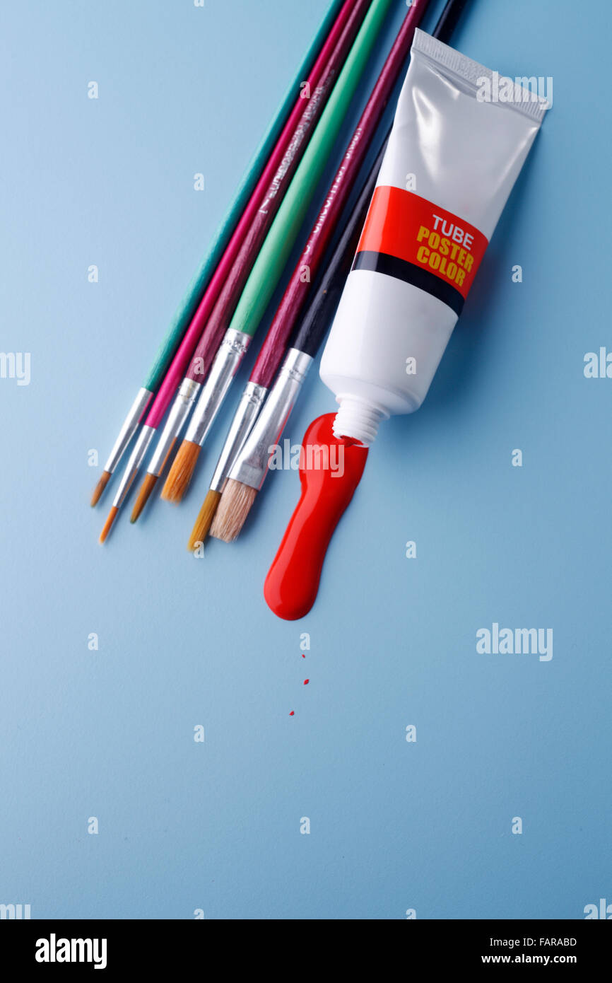 Multiple paintbrushes with a tube of paint isolated on blue background ...