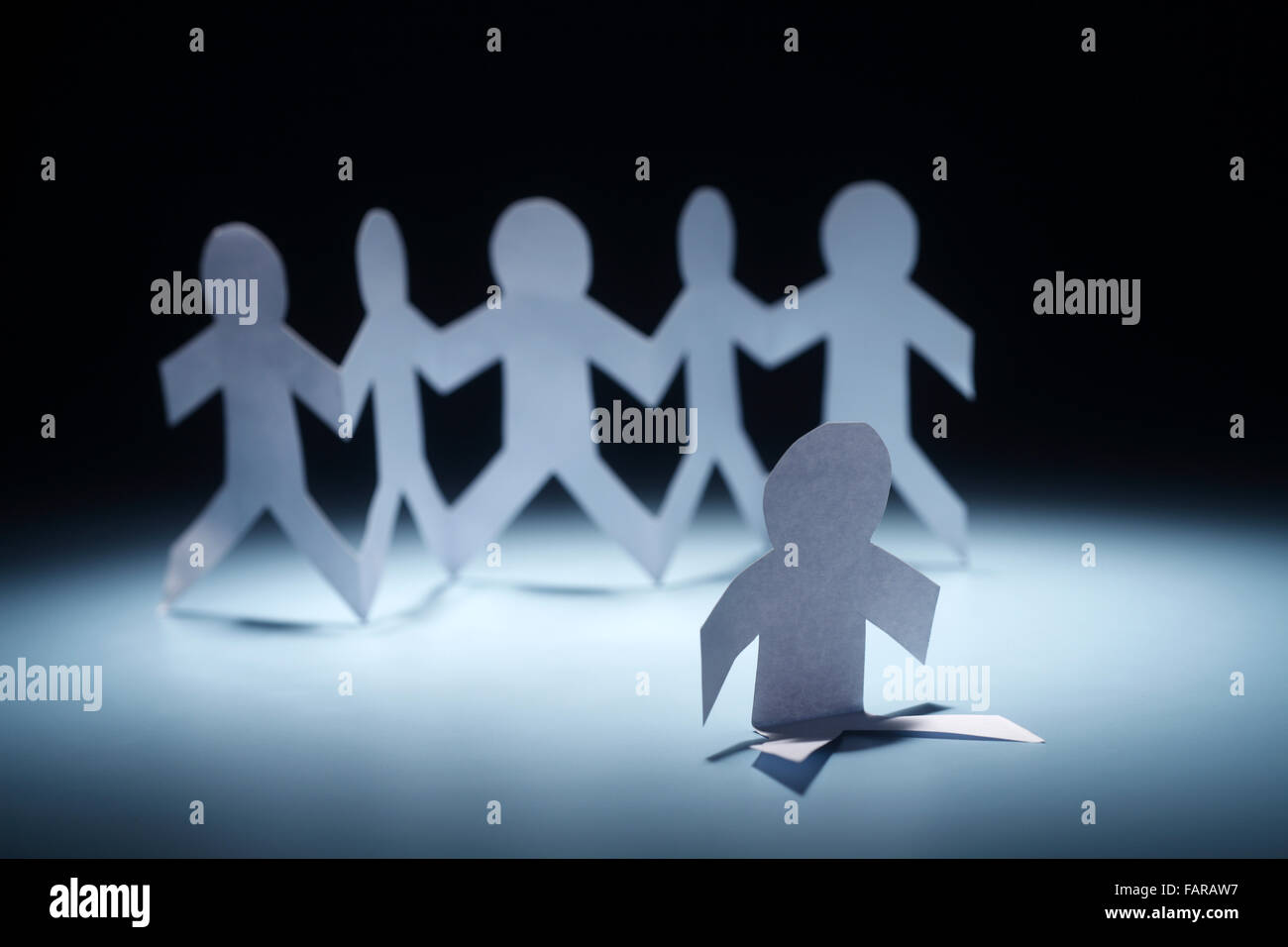 Paper men holding hands together while one of them is away from the ...