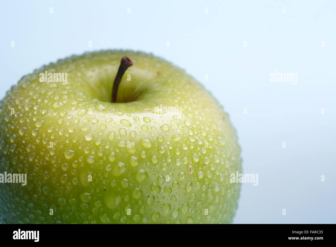 Wet green apple covered by water drops on coloured background ...