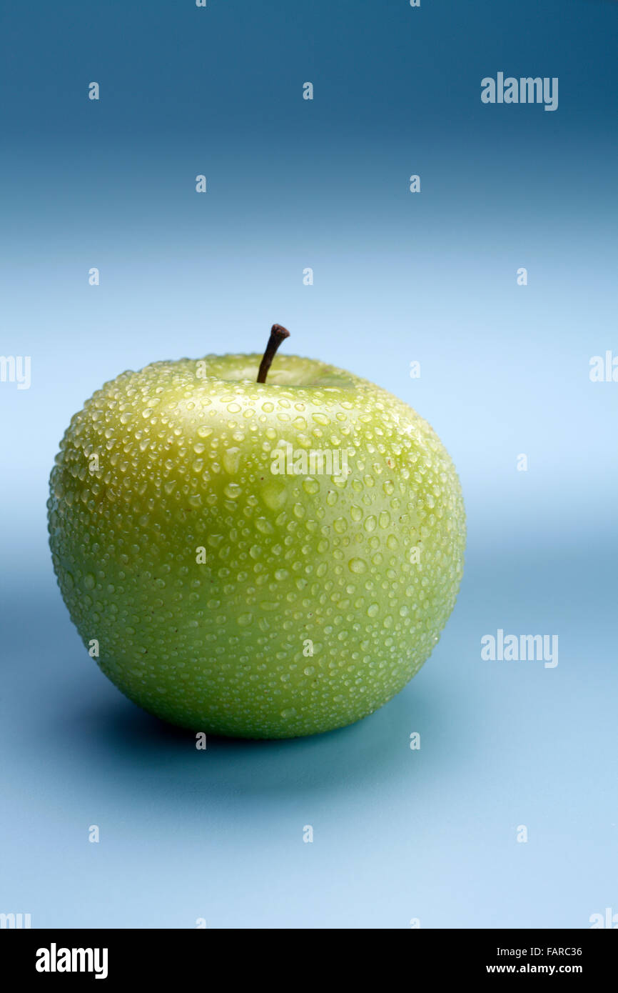 Wet green apple covered by water drops on coloured background ...