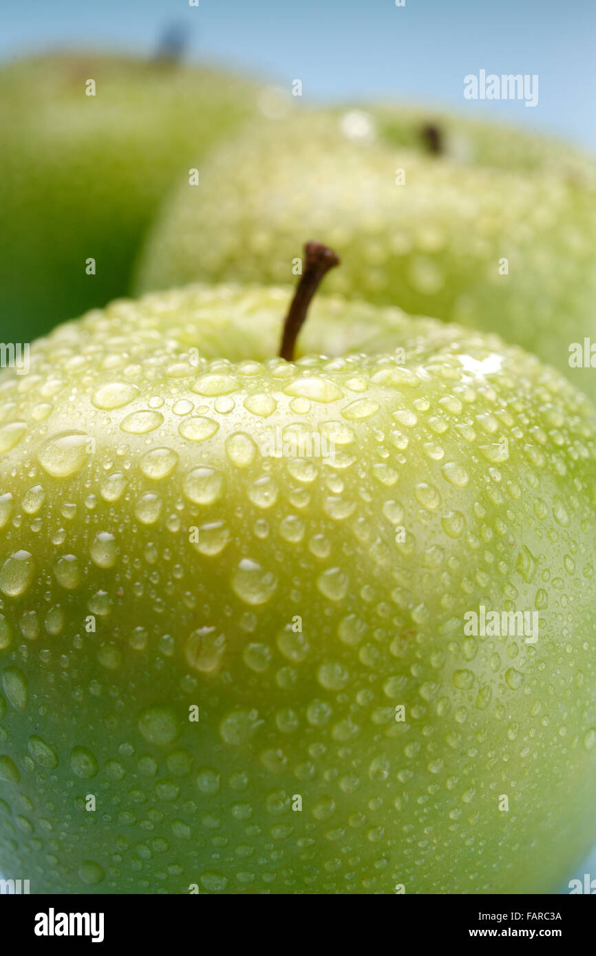 Wet green apple covered by water drops on coloured background ...